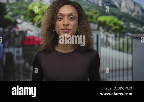 Woman clutching chest outdoors by iron fence and building in urban ...