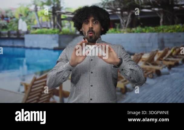 Man with raised hands and open mouth at poolside outdoors showing ...