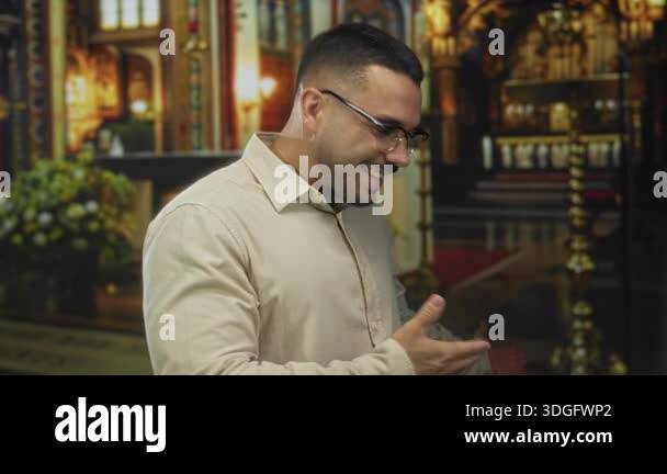 Young hispanic man beckons with finger inside church building with ...