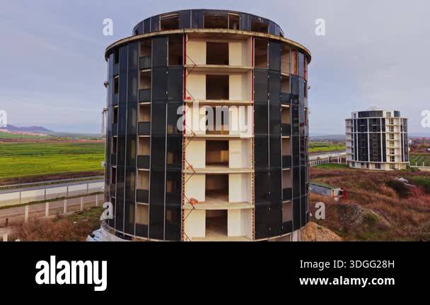 Large, partially built round buildings stand in a green field ...