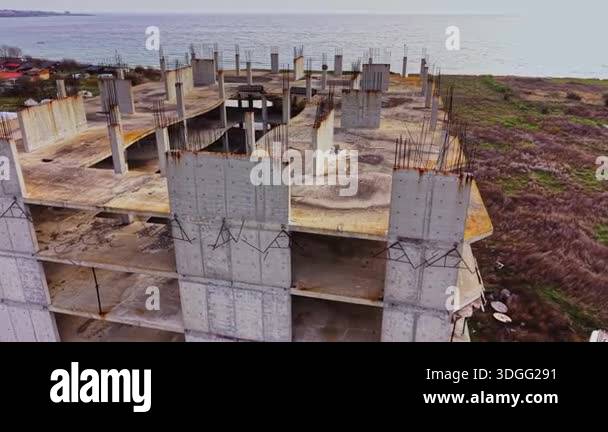 Aerial view of an unfinished building by the sea, showcasing rusted ...