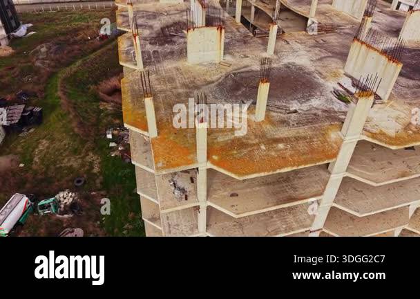 An aerial view captures a large unfinished building with rusted rebar ...