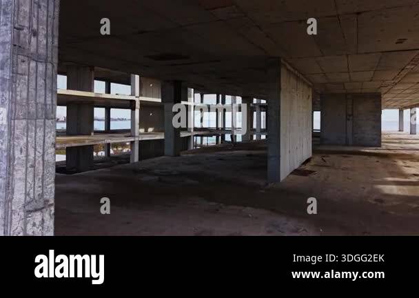 Dusty interior of an unfinished concrete building reveals open spaces ...