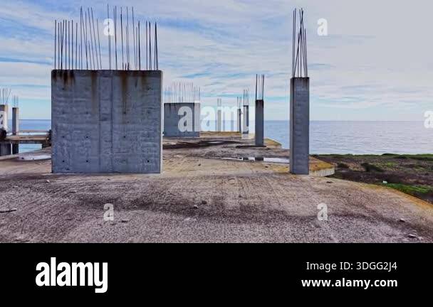 Aerial view of a construction site near the ocean. Concrete pillars ...