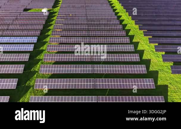 Rows of solar panels stretch across a large green field, soaking up ...