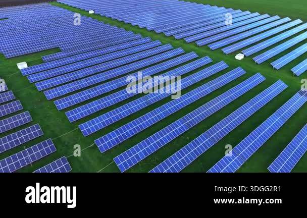 An extensive field of solar panels captures sunlight in a green ...