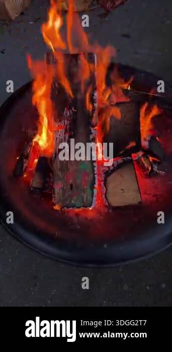 Bright dancing flames in a metal fire pit with burning wood logs ...