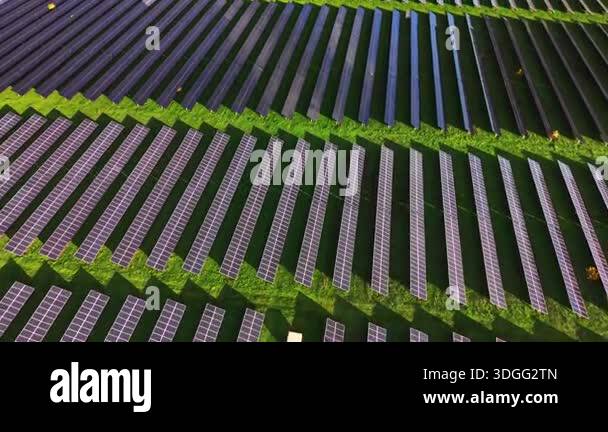 Wide aerial view of solar panel fields arranged in neat rows across a ...