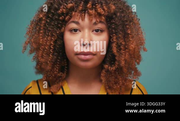 Pretty young woman wearing yellow t-shirt smiles warmly on blue ...