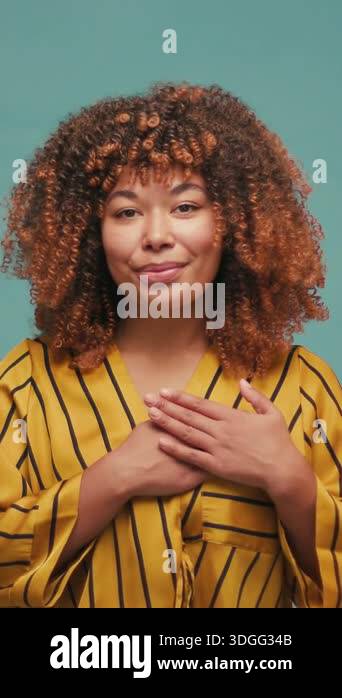 Hispanic woman says thank you with gesture with hands on heart on blue ...