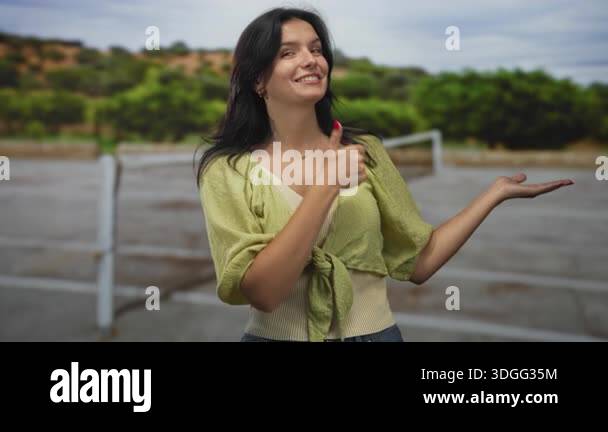 Young hispanic woman giving thumbs up with extended hand on sunny ...