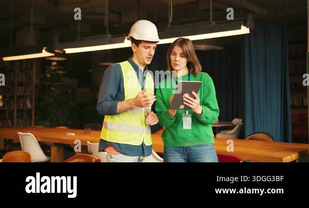 Professional female architect and male builder in hard hat reviewing ...
