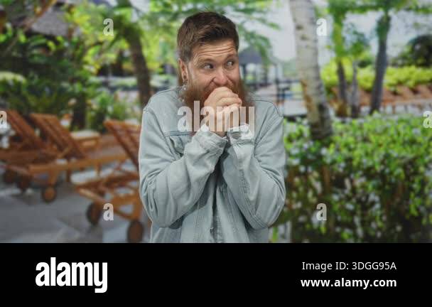 Man with red beard shrugs palms up amid lush green foliage and tall ...