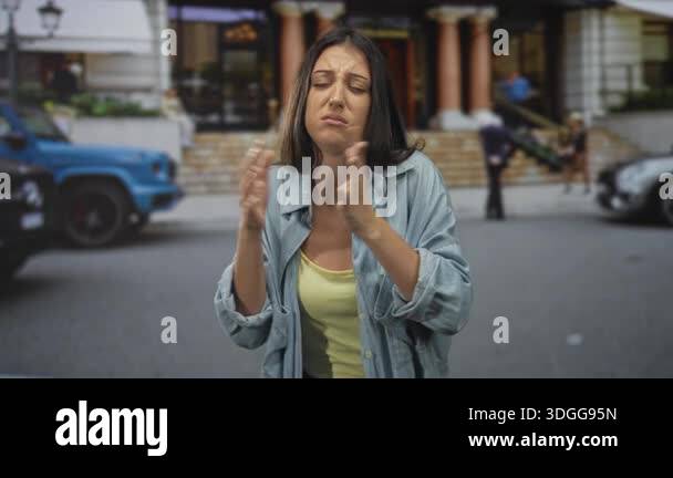 Woman with hands clasped pleading on a city street in front of a ...