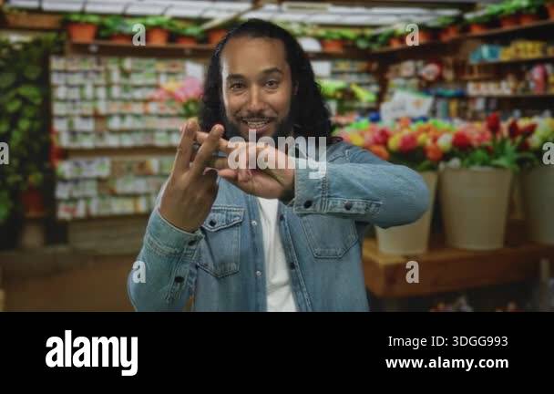 Man making hashtag sign with hands among flowers in building flower ...