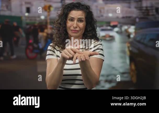 Woman makes begging gesture with open hand and curled finger on street ...