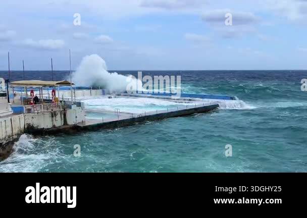 Dramatic view of large ocean waves crashing over and flooding concrete ...