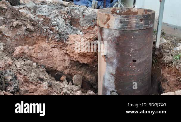 Large, rusty metal piling casing at an excavated construction site ...