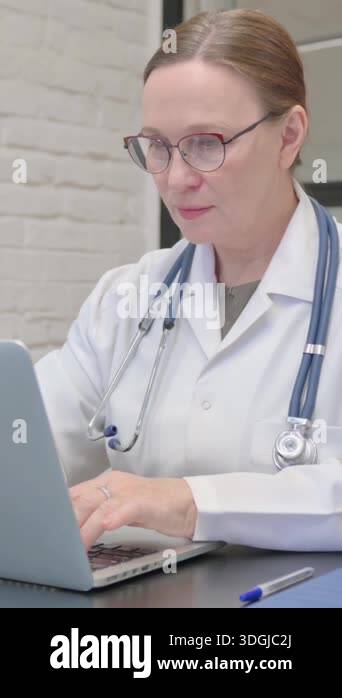 Old Lady Doctor Typing on Laptop in Office, vertical video Stock Video ...