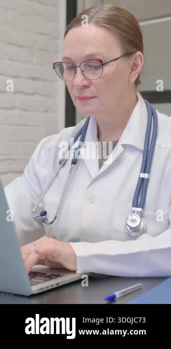 Gesture of Approval by Old Lady Doctor Using Laptop, vertical video ...