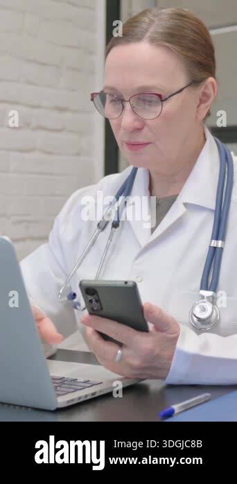 Old Lady Doctor Using Laptop and Phone, vertical video Stock Video ...