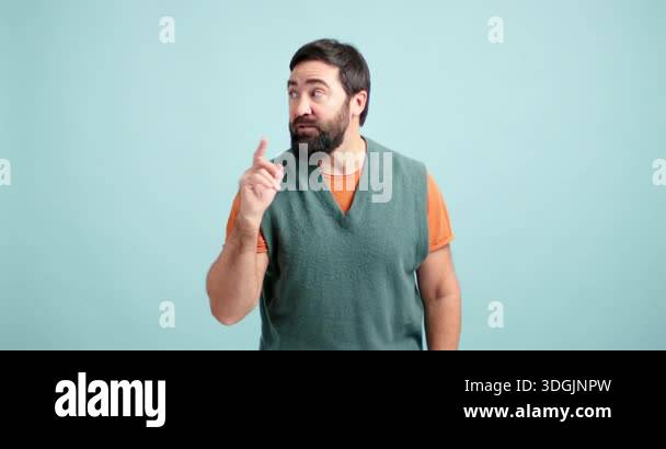 Expressive middle aged man with a beard pointing to his side against a ...