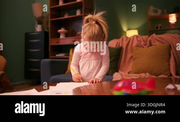 Creative little girl enjoying drawing with colored pencils on paper in ...