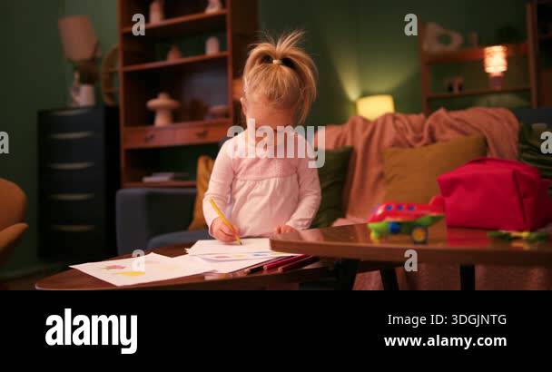 Cute toddler drawing with colorful pencils on paper in the living room ...