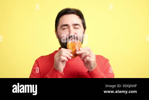 Slow motion footage of a hungry man savoring a tasty pastry against a ...