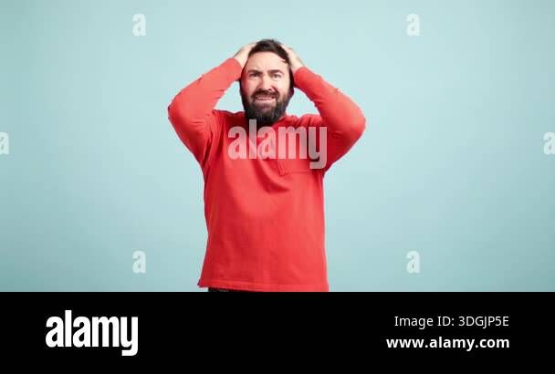 Confused man with a beard looking shocked and stressed against a solid ...