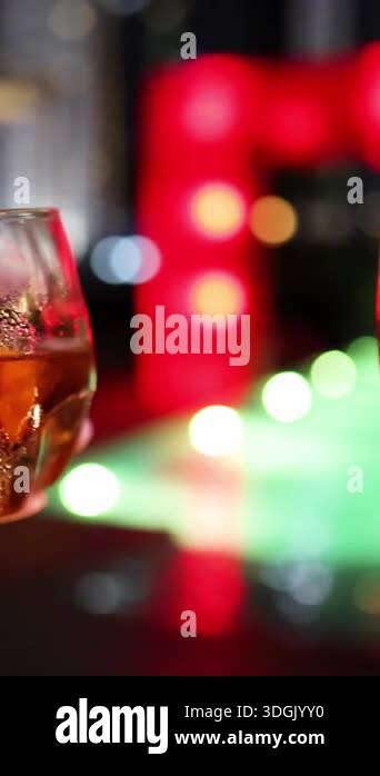 Two hands toast with cocktail glasses filled with ice and amber liquid ...
