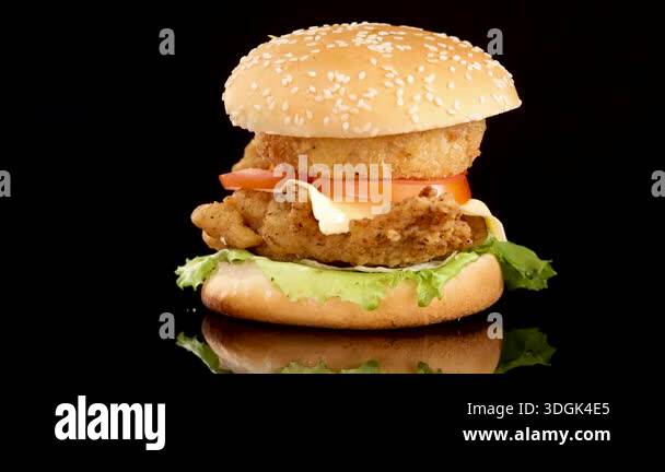 A crispy fried chicken burger with lettuce, tomato, cheese, and onion ...