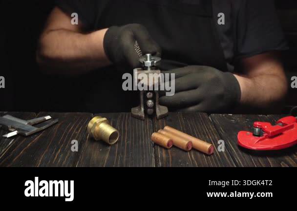 A plumber uses tools to work on plumbing components. There are various ...