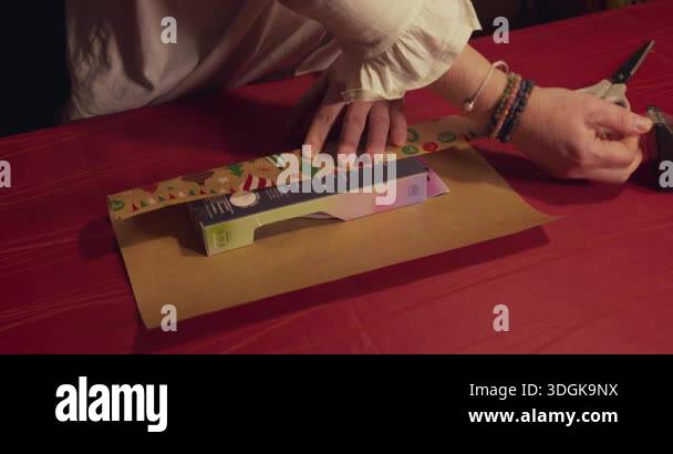 A woman is cutting a brown wrapping paper with scissors. The paper is ...