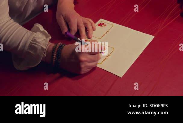 A white card with a red border sits on a red bedspread. The card has a ...