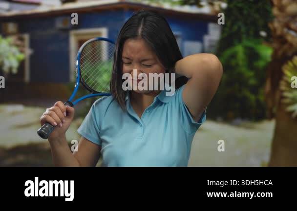 Chinese woman holding a tennis racket in a park feels neck pain after ...