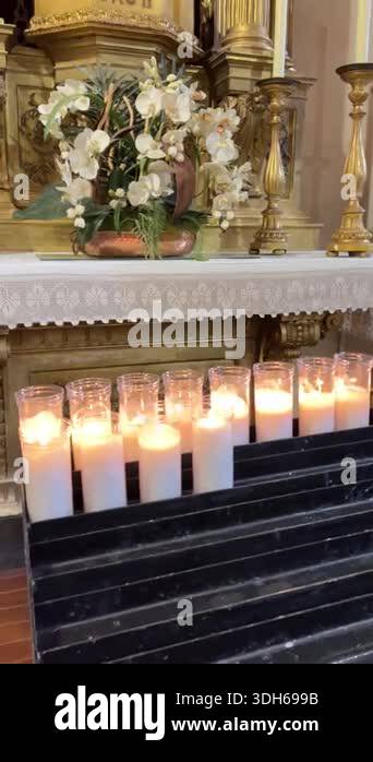 Row of white devotional candles burning in glass holders inside a ...
