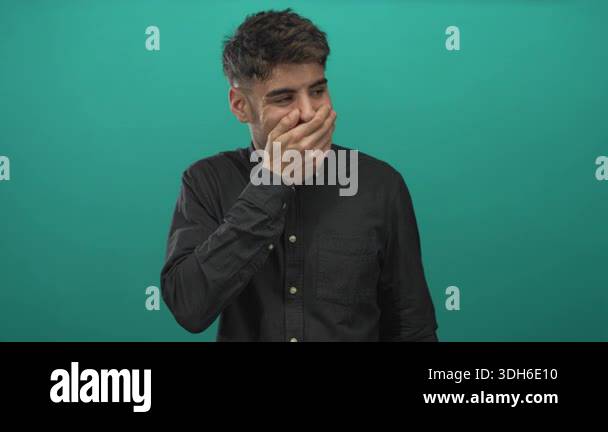Young hispanic man covers mouth with hand and smiles shyly against ...