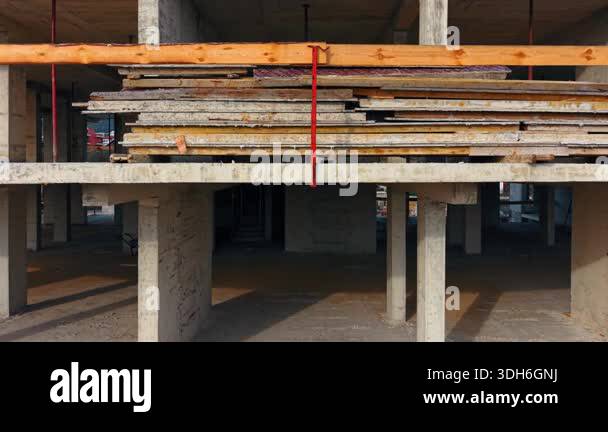 A construction site shows a large stack of building materials resting ...