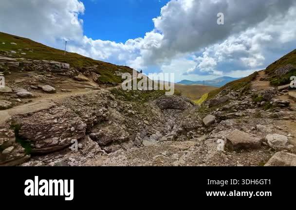 Hiking trail through rocky terrain under a cloudy sky with distant ...
