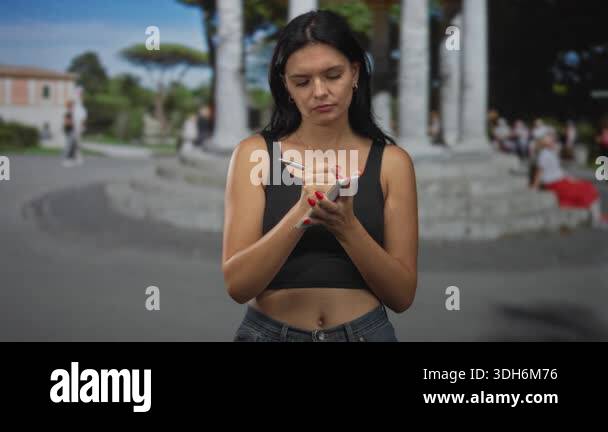 Woman standing writing in notepad with pen in building courtyard with ...
