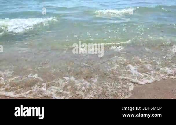 Sea waves with turquoise transparent water rolling onto sand of sandy ...