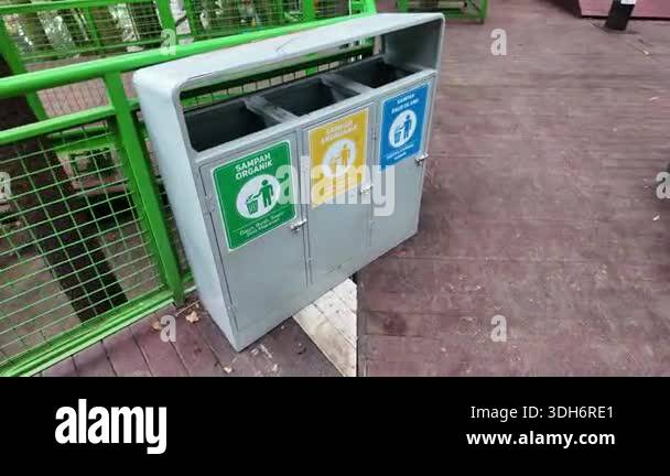 Close-up of a recycling bin with green, yellow, and blue sections. The ...