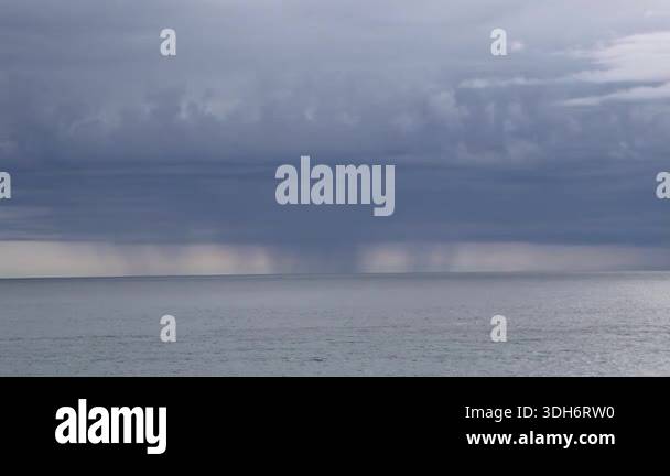 Distant rain falls from heavy clouds over calm ocean horizon Bogliasco ...