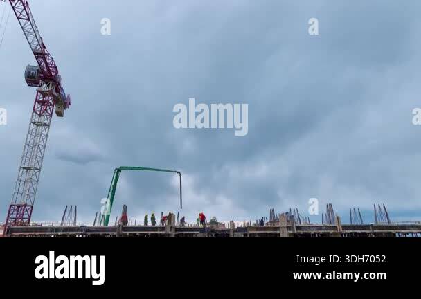 Aerial footage shows workers leveling fresh concrete while cranes move ...