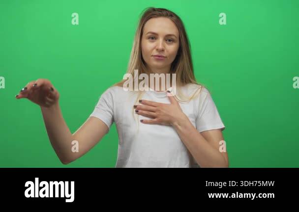 Woman raising hand in a pledge gesture standing against a green ...
