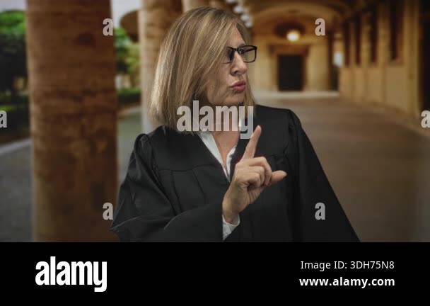 Woman judge wearing black robe and glasses points finger in old town ...