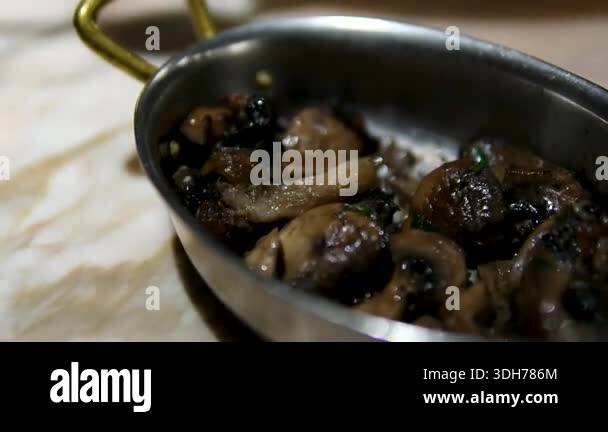 A slow-motion close-up of sliced small porcini mushrooms being fried in ...