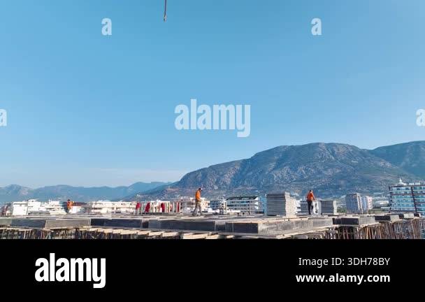 Cranes transport materials while workers secure the structure for the ...