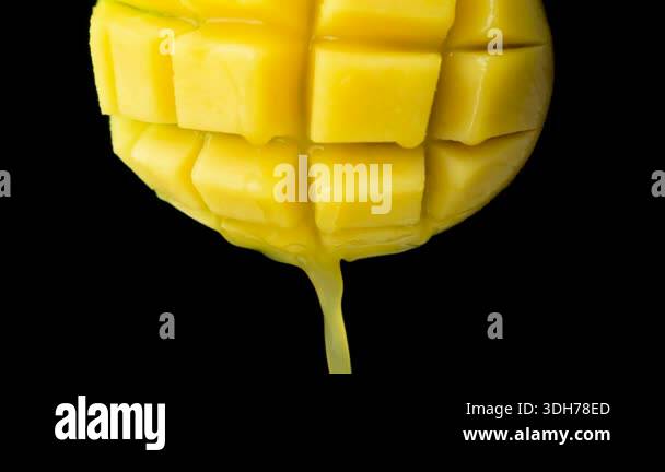 Macro of mango juice dripping from sliced fruit cubes, slow motion ...